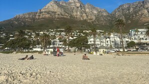Uma praia com pessoas tomando sol e uma montanha ao fundo.
