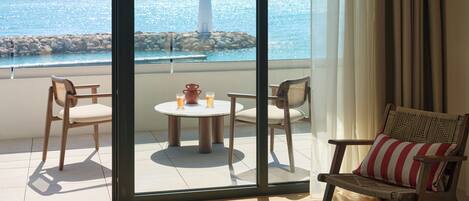 Uma varanda com vista para o mar e um farol, equipada com cadeiras e uma mesa.