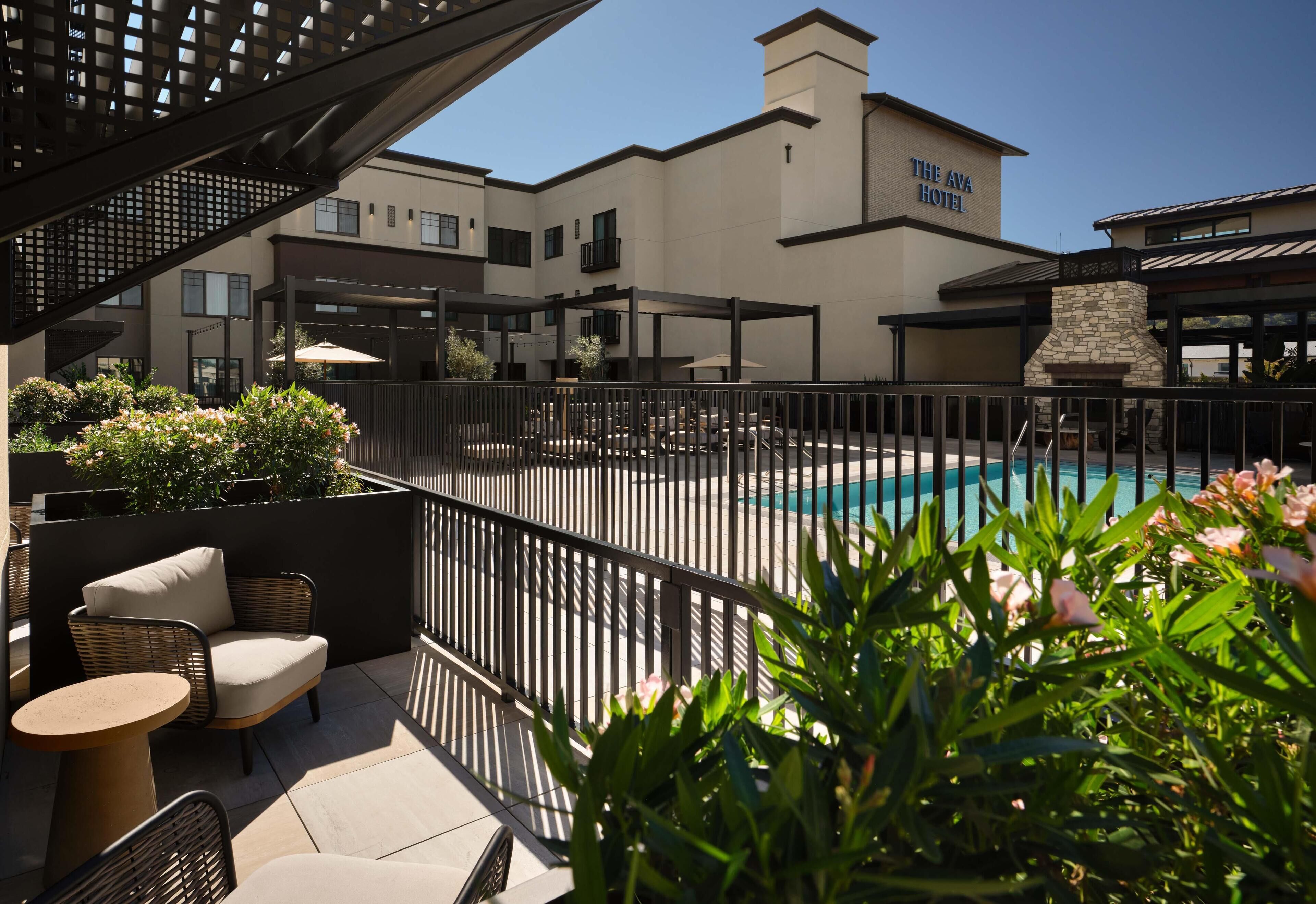 Pátio de hotel com piscina, área de estar ao ar livre e varanda coberta.
