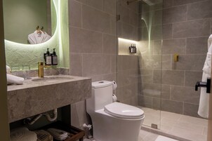Uma casa de banho moderna com lavatório de mármore, sanita e cabine de duche com portas de vidro.
