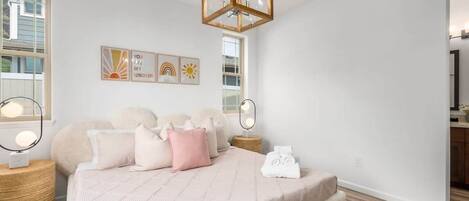 Quarto com cama grande, abajures e quadros nas paredes.