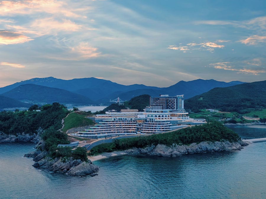 Um cruzeiro atracado em um resort costeiro, com vários decks e um cenário montanhoso.