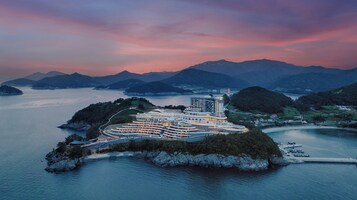 Hotel à beira-mar com vários edifícios, uma ponte e montanhas ao redor.