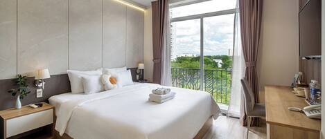 Quarto de hotel moderno com uma cama grande, uma escrivaninha e varanda com vista.