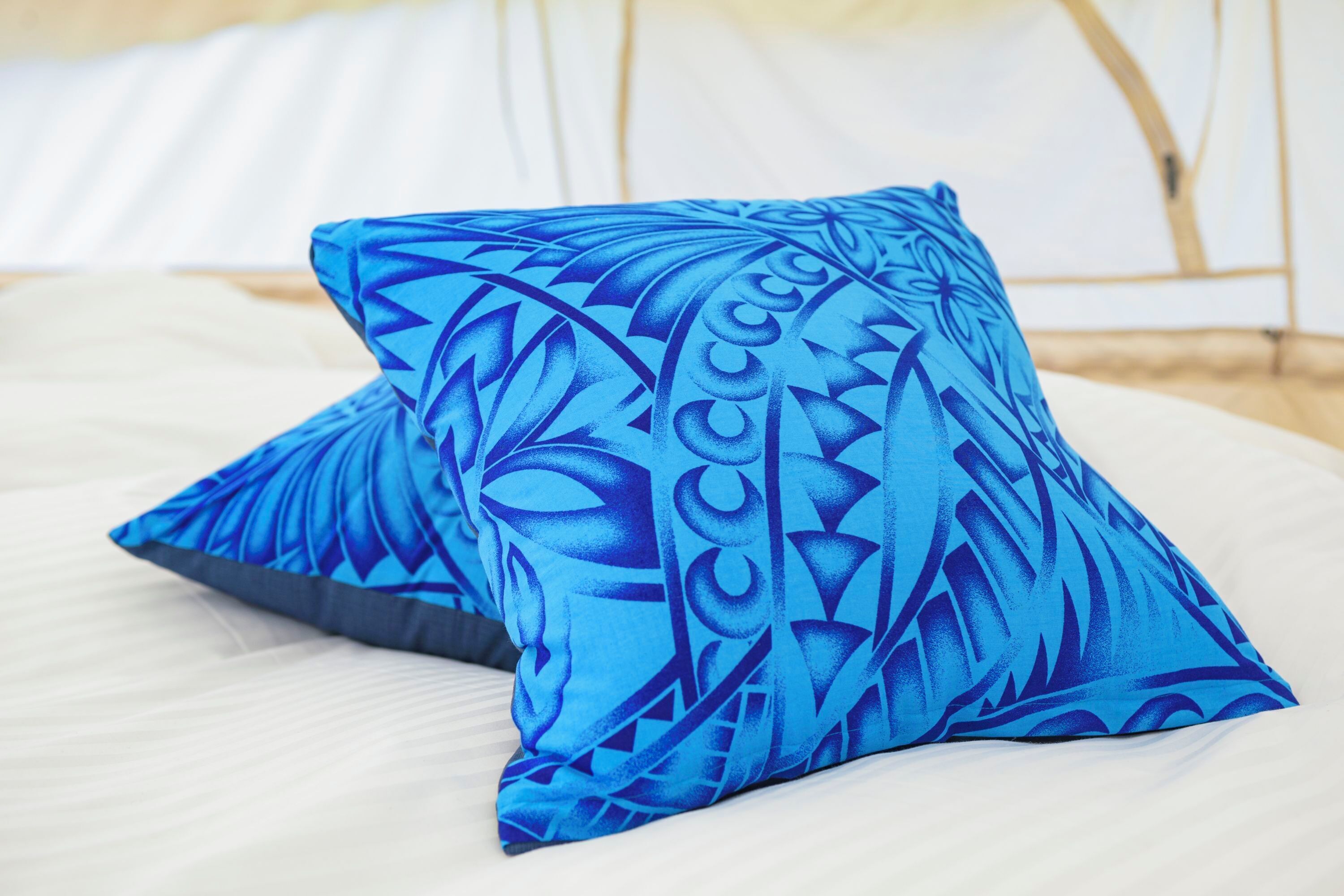 Uma cama com um travesseiro de padrão azul e um cobreleito branco.