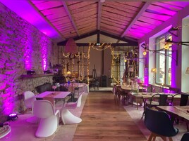 Um restaurante com mesas e cadeiras de madeira, paredes de pedra e luzes de corda.