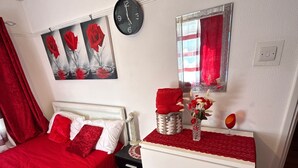 Quarto com uma cama, penteadeira, relógio e uma pintura.