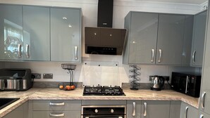 Uma cozinha moderna com armários cinza, eletrodomésticos de aço inoxidável e forno embutido.