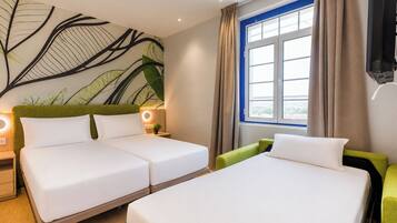 Quarto de hotel com duas camas, uma janela grande com cortinas, um mural na parede e uma televisão.