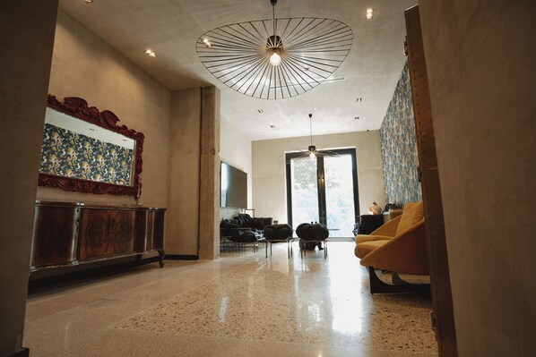 Um hall amplo com piso lustroso, um espelho grande, um armário de madeira clássico e uma poltrona amarela moderna.