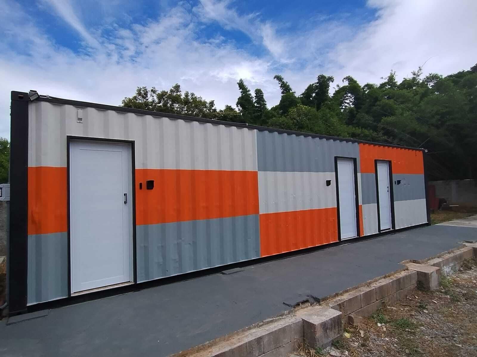 Um edifício industrial térreo com fachada em metal corrugado, com duas portas e uma pequena janela.