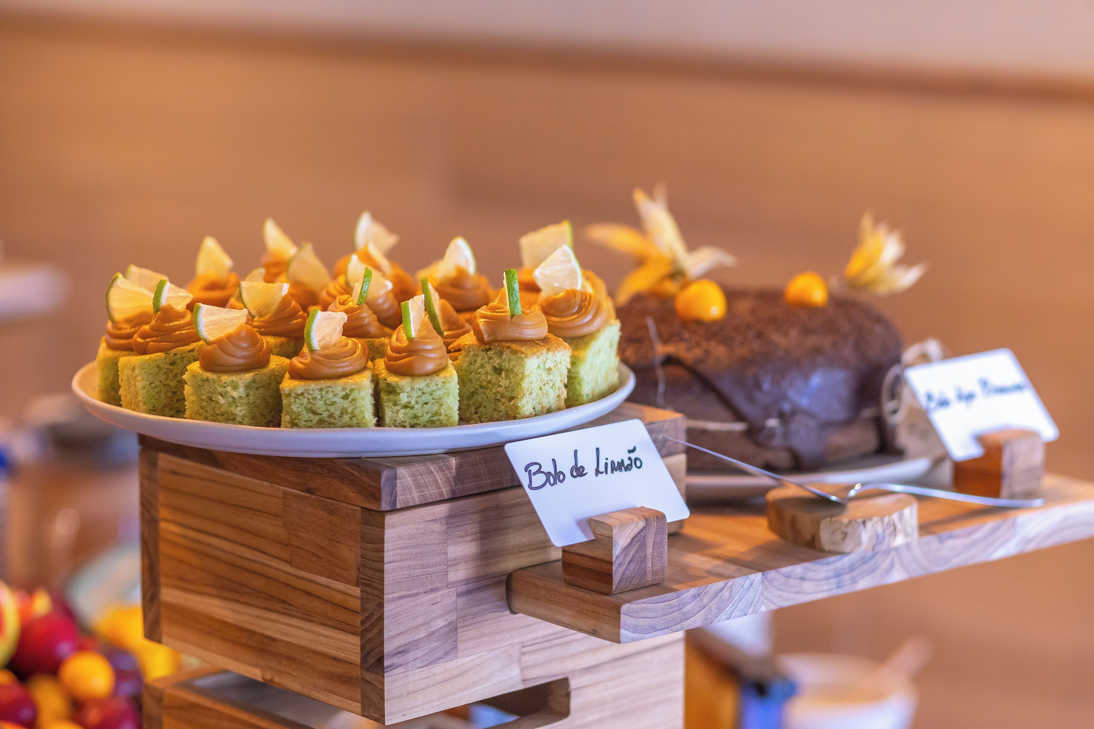 Uma mesa com sobremesas, incluindo um bolo de limão, sobre um suporte de madeira.