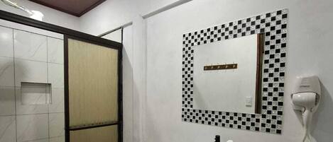 Uma casa de banho moderna com sanita, lavatório e espelho com moldura de azulejos decorativos.