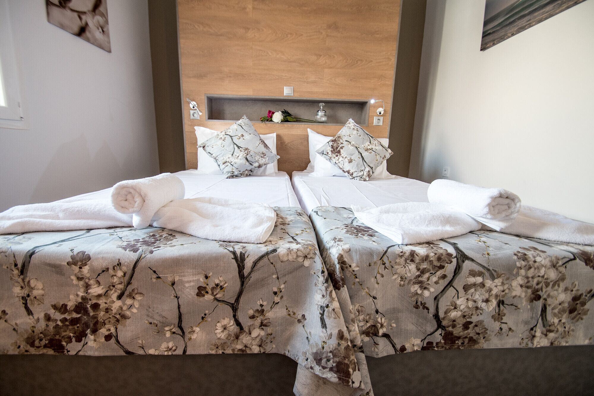 Quarto de hotel com uma cama, almofadas e uma mesa de cabeceira.