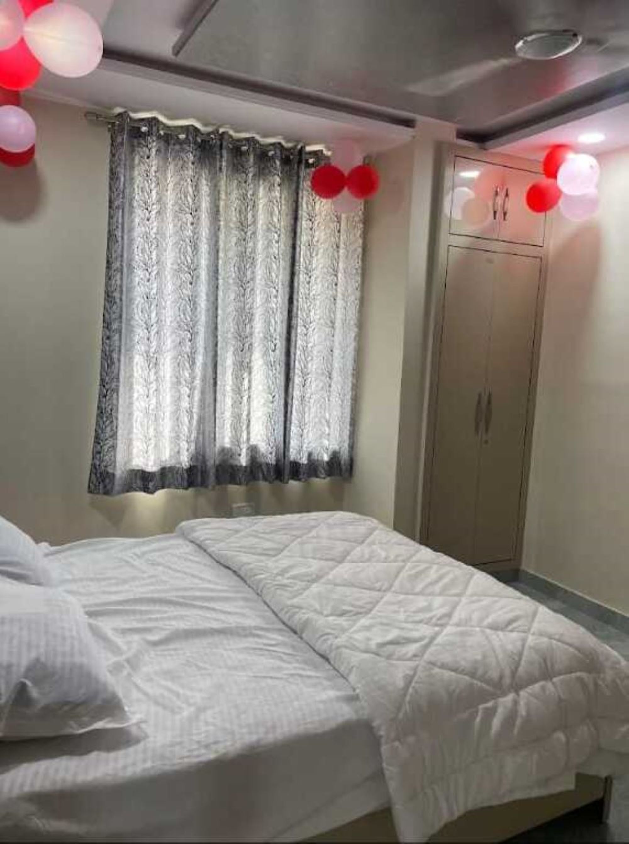Quarto com cama, cortinas e guarda-roupa.