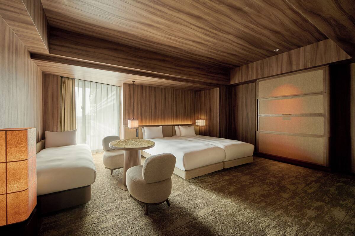 Quarto de hotel com uma cama grande, uma mesa redonda pequena, uma cadeira e um guarda-roupa.