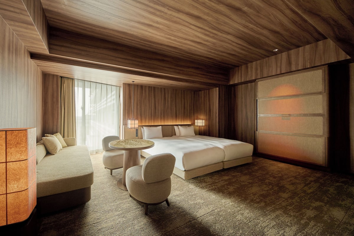 Quarto de hotel com uma cama grande, área de estar com uma mesa e um guarda-roupa.