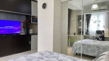 Quarto moderno com TV, espelho e duas camas com roupa de cama estampada.