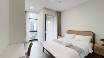 Quarto de hotel moderno com uma cama grande, uma escrivaninha e uma cadeira.