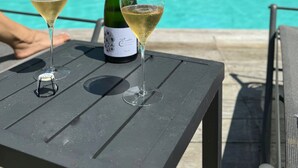 Uma garrafa de champanhe e dois copos sobre uma mesa perto da piscina.