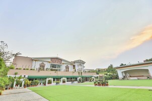 Um hotel com um pátio amplo, área de estar coberta ao ar livre e um edifício com arquitetura clássica.