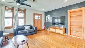 Uma sala de estar moderna com um sofá de couro, uma mesa de centro, uma televisão e um armário de madeira.