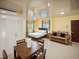 Quarto de hotel com cama, sofá, mesa de jantar e janela com cortinas.