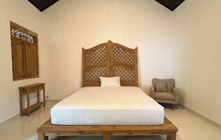 Quarto com estrutura de cama de madeira, mesa de cabeceira, cadeira e um painel decorativo de madeira na parede.