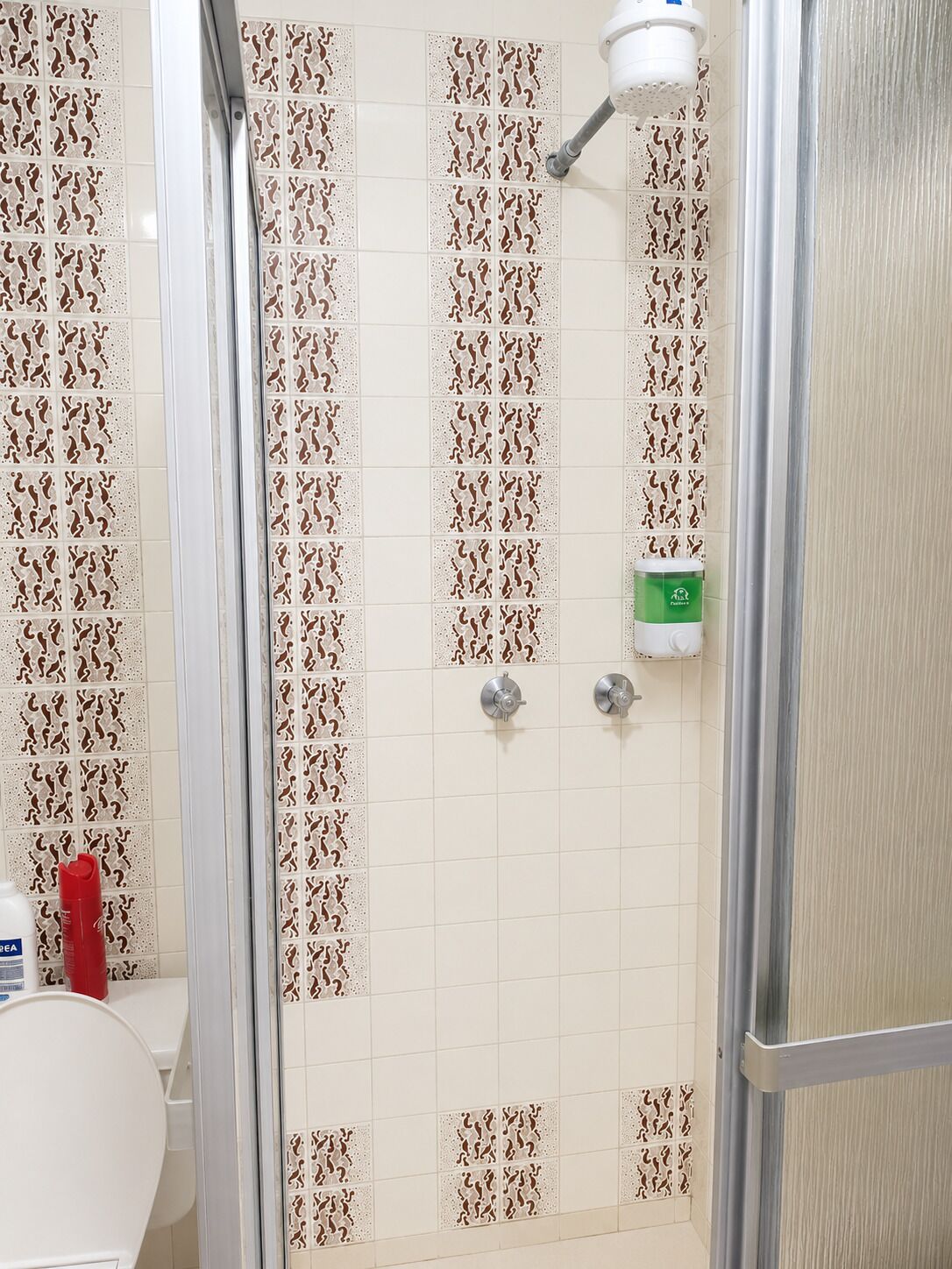 Um chuveiro com azulejos estampados, um vaso sanitário e uma pia.