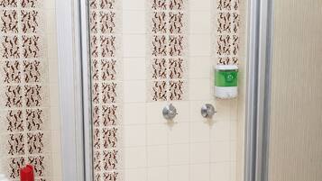 Um chuveiro com azulejos estampados, um vaso sanitário e uma pia.