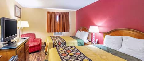 Quarto de hotel com duas camas, televisão, escrivaninha e uma cadeira vermelha.