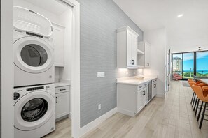 Cozinha moderna com eletrodomésticos embutidos, parede decorada em cinza e vista para o oceano.