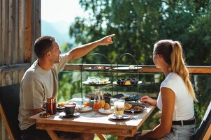 Uma mesa de madeira com um suporte escalonado para servir, diversos alimentos e bebidas.