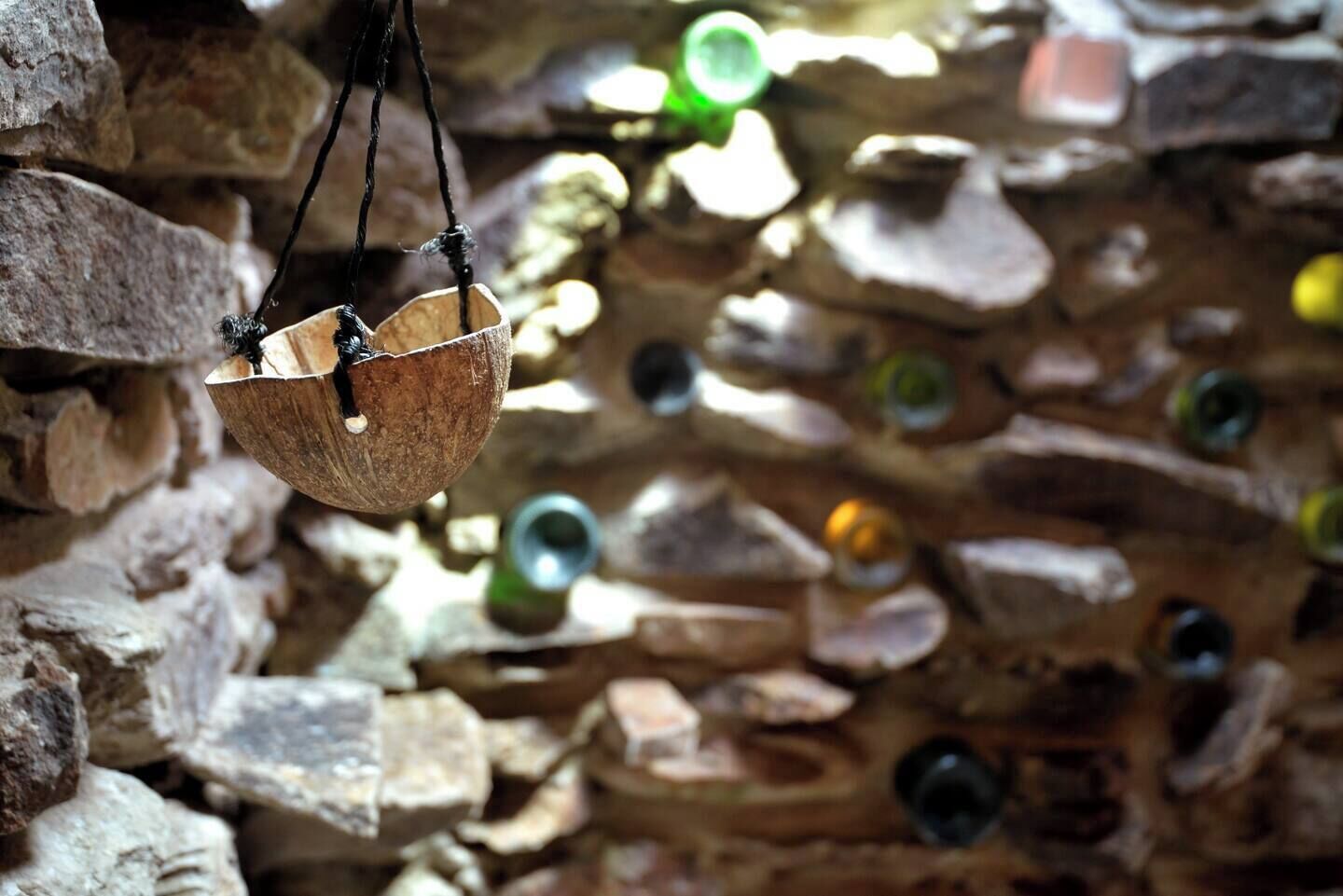 Uma parede de pedra com um cesto suspenso contendo uma planta.