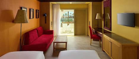 Quarto de hotel com duas camas, um sofá vermelho, uma escrivaninha de madeira, uma televisão e vista para a área da piscina.