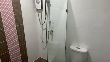 Uma casa de banho com chuveiro, sanita e termoacumulador de água na parede.