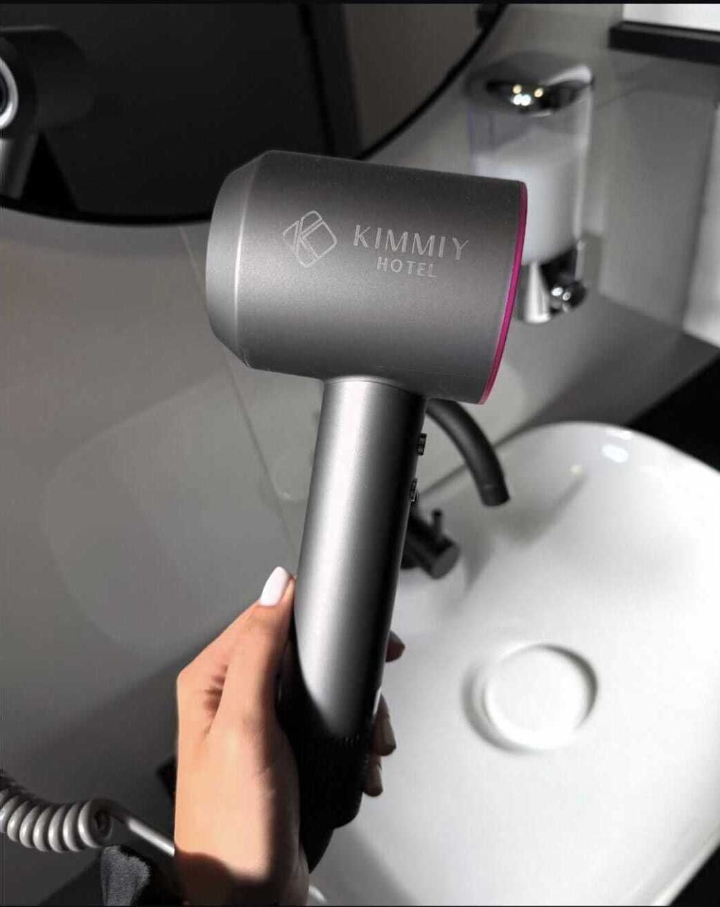 Uma mão segurando um secador de cabelo com o texto "KIMMIY HOTEL".