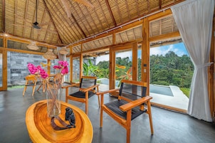 Quarto espaçoso com grandes janelas, móveis de madeira e vista para um verde exuberante.
