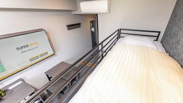 Quarto de hotel com cama, escrivaninha, cadeira e televisão exibindo 'SuperHotel'.