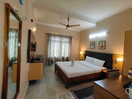 Quarto de hotel com cama, mesa de cabeceira, abajur, ventoinha no teto e espelho.