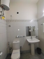 Uma casa de banho com sanita, lavatório, chuveiro e espelho.