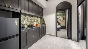 Uma cozinha moderna com armários escuros, painel de azulejos e uma geladeira.