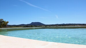 Céu azul e límpido acima de uma piscina, com uma montanha ao fundo.