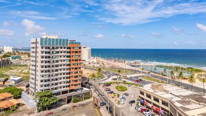 Um hotel moderno com vários andares, estacionamento e vista para o oceano.