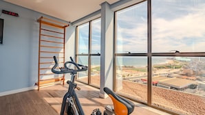 Quarto espaçoso com grandes janelas, uma bicicleta e uma escada de madeira.