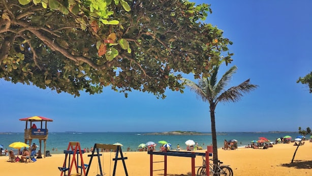 Uma praia com uma torre de salva-vidas, balanços e uma bicicleta.