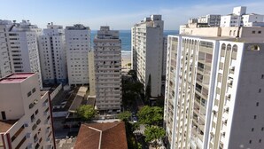Hotel alto com vários andares, vista para a praia e céu claro.