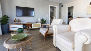 Uma sala de estar moderna com sofá, poltrona e uma mesinha com uma tigela verde.