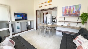 Uma cozinha moderna com área de refeições, uma televisão fixada acima do balcão e um quadro na parede.