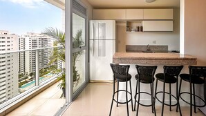 Uma cozinha moderna com uma janela grande, teto de madeira e um espaço bar com quatro banquetas.